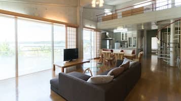 Uma sala de estar ampla com sofá, televisão e mesa de jantar.