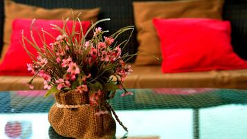 Um pequeno vaso de sacos de juta com flores cor-de-rosa sobre uma mesa de vidro.