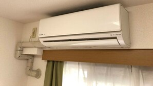 Ar condicionado branco da Panasonic fixado em parede, com uma prateleira de madeira abaixo.
