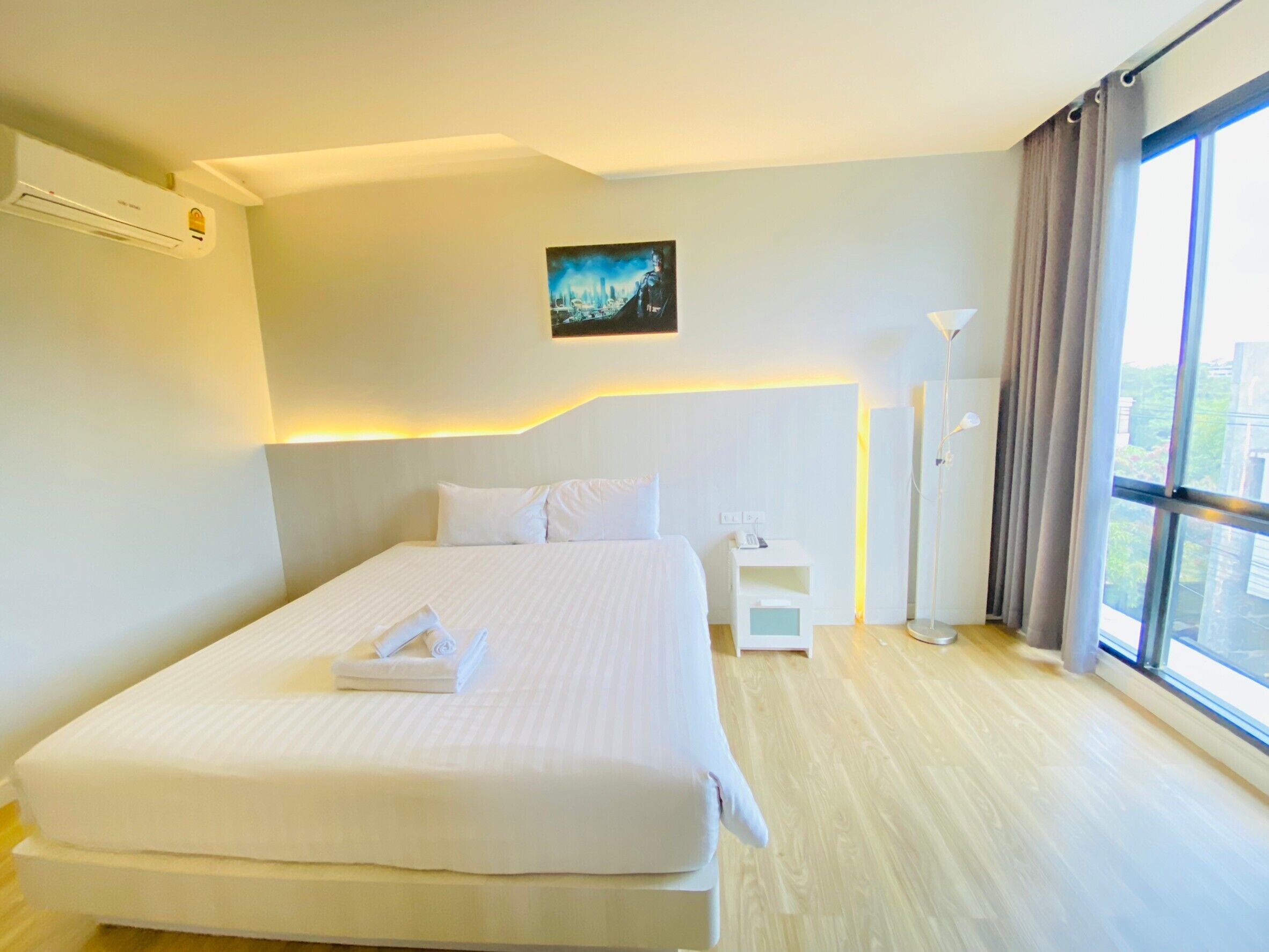 Quarto de hotel com uma cama grande, uma mesa de cabeceira com telefone e uma janela com cortinas.