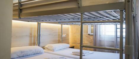 Quarto com beliche, duas camas, cada uma com travesseiro e toalha enrolada.
