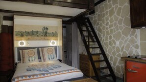 Um quarto com cama, escada, cômoda e parede com padrão de pedra.