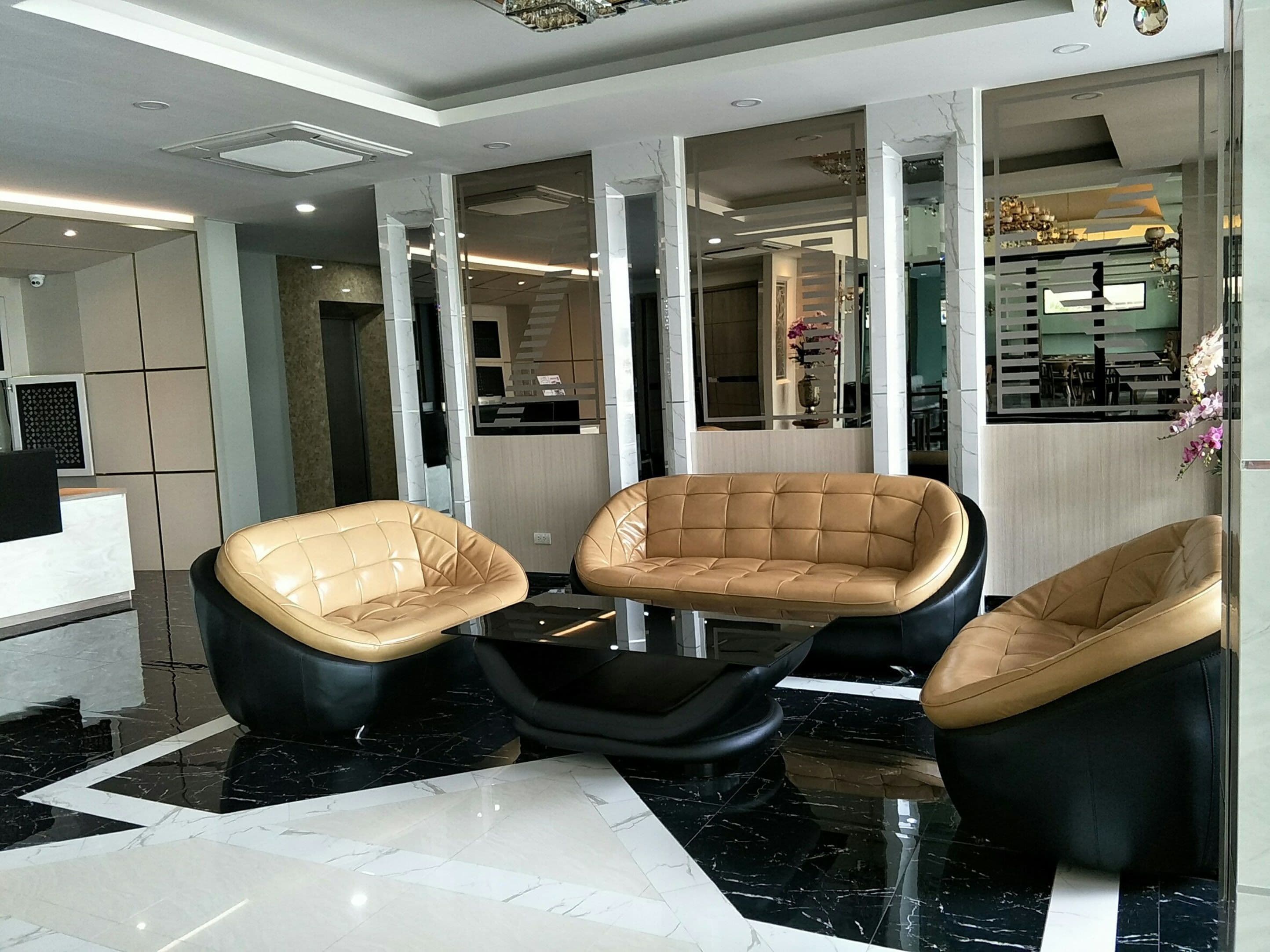 Um lobby moderno com piso de mármore preto e branco, poltronas de couro e uma mesa de centro de vidro.