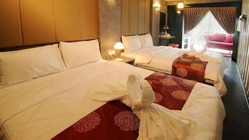 Quarto de hotel com duas camas, cada uma com roupa de cama branca e colcha vermelha estampada. Há luminárias laterais e uma janela com cortinas.