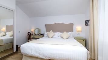Quarto bem arrumado com uma cama grande, mesa de cabeceira com abajur, espelho e um criado-mudo.