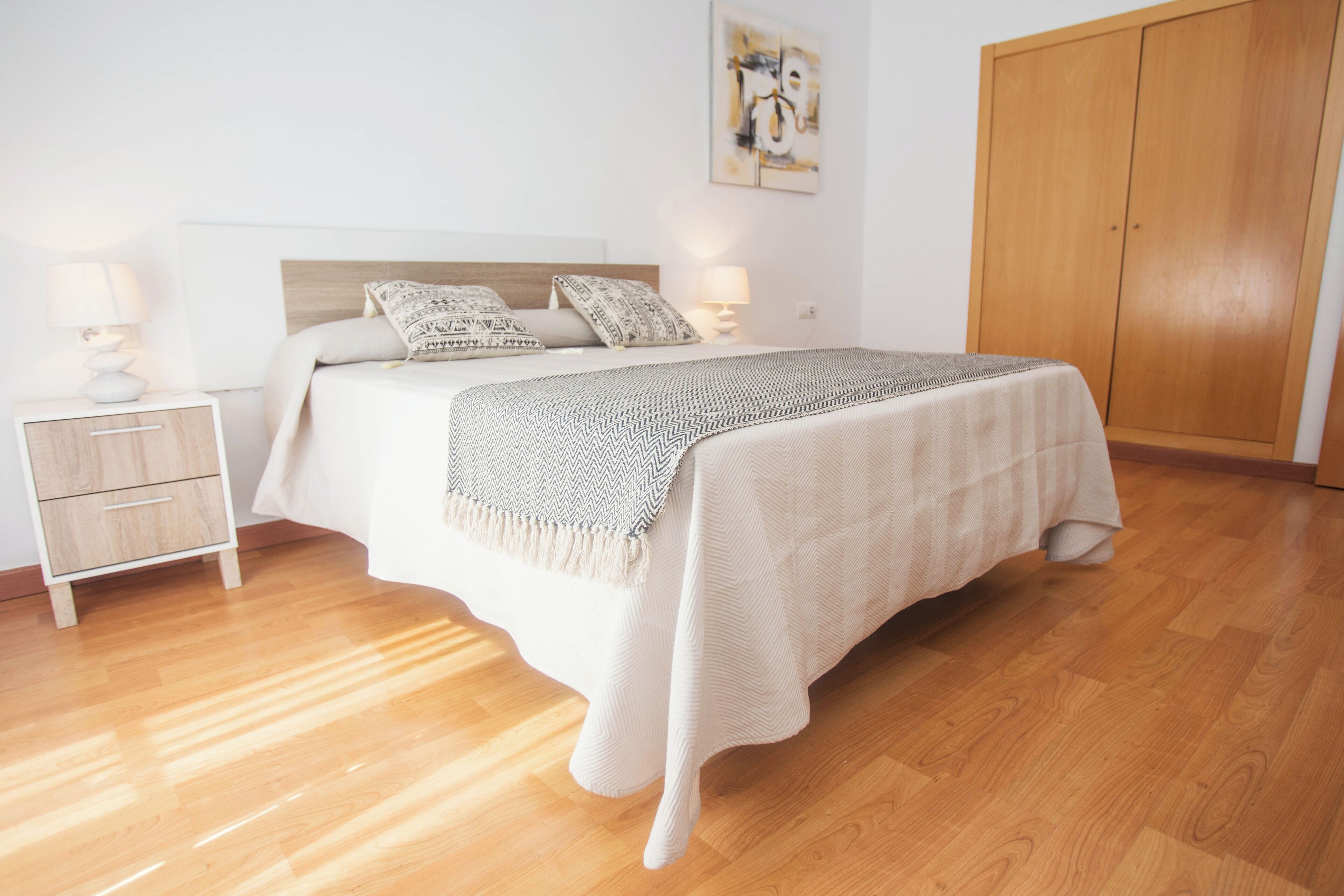 Quarto com cama, mesas de cabeceira, guarda-roupa e uma parede com obras de arte.