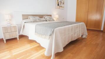Quarto com cama, mesas de cabeceira, guarda-roupa e uma parede com obras de arte.