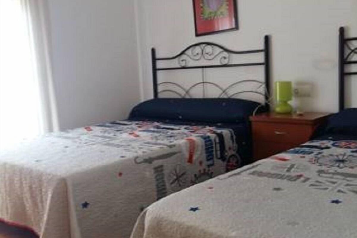 Quarto com duas camas, uma mesa de cabeceira com abajur e um quadro na parede.