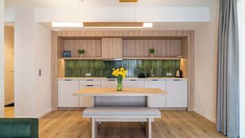 Cozinha moderna com armários de madeira, painel de parede verde e um banco ao centro.
