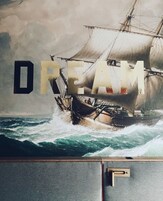 Um cartaz com um navio em mar agitado e a palavra "DREAM" em destaque.