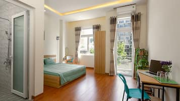 Quarto moderno com uma cama, uma escrivaninha com um laptop e uma área de chuveiro.