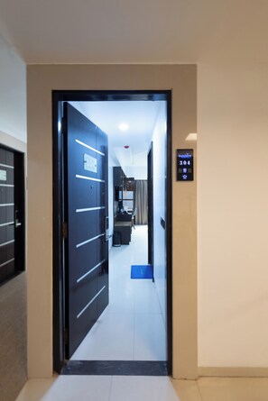 Entrada de um quarto de hotel, com uma porta que dá para um corredor, uma mesa de recepção e um leitor de cartão-chave digital.