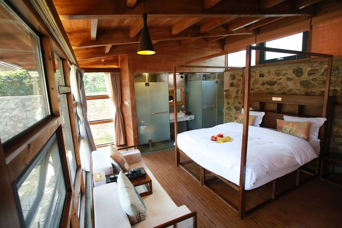 Quarto com cama de dossel, teto de madeira e parede de pedra.