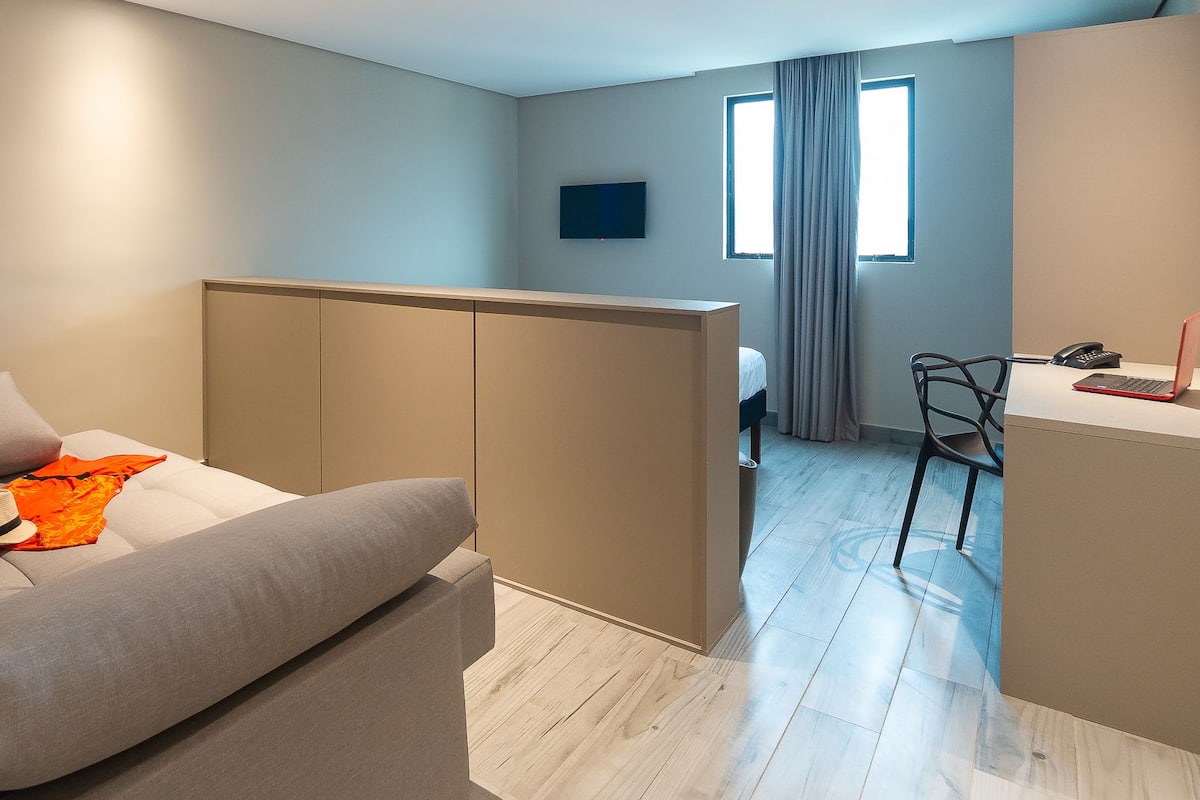 Quarto de hotel moderno com sofá, escrivaninha e cadeira.