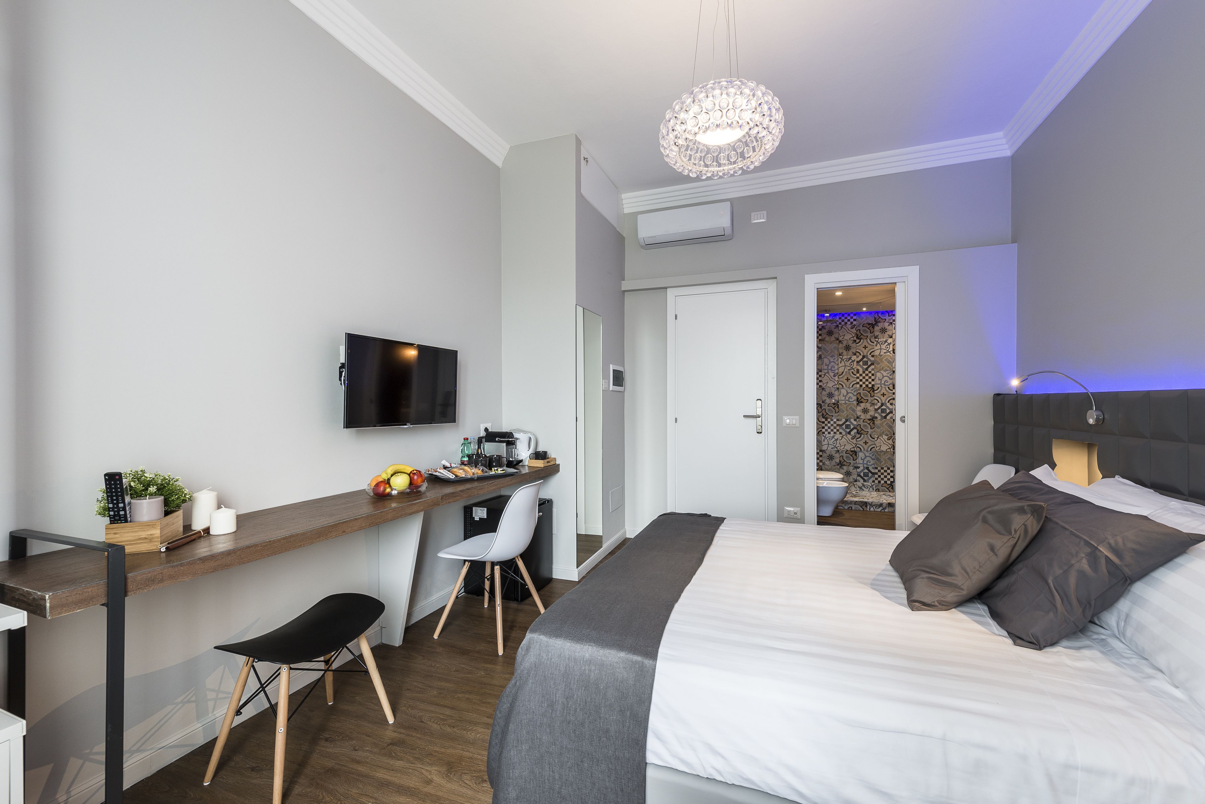 Quarto de hotel moderno com cama, escrivaninha e área de estar.
