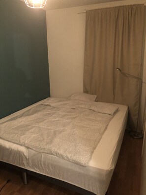 Uma cama de solteiro com colcha estampada, um abajur e uma cortina.
