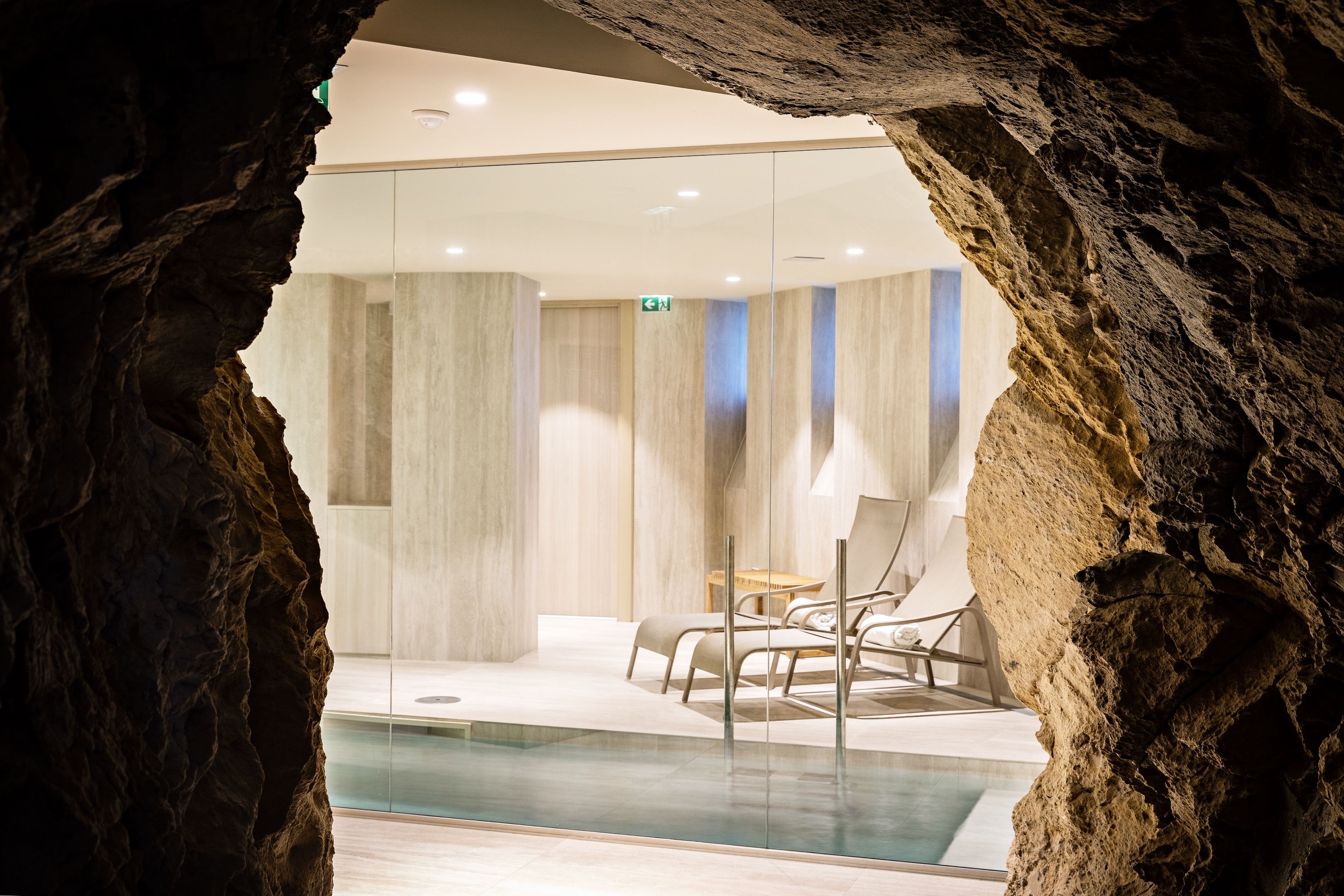 Área de spa com parede de vidro, piscina e assentos.