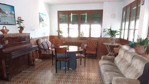 Uma sala de estar com piso estampado, móveis de madeira e um piano.