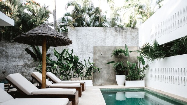 Uma área à beira da piscina com espreguiçadeiras e uma piscina pequena.