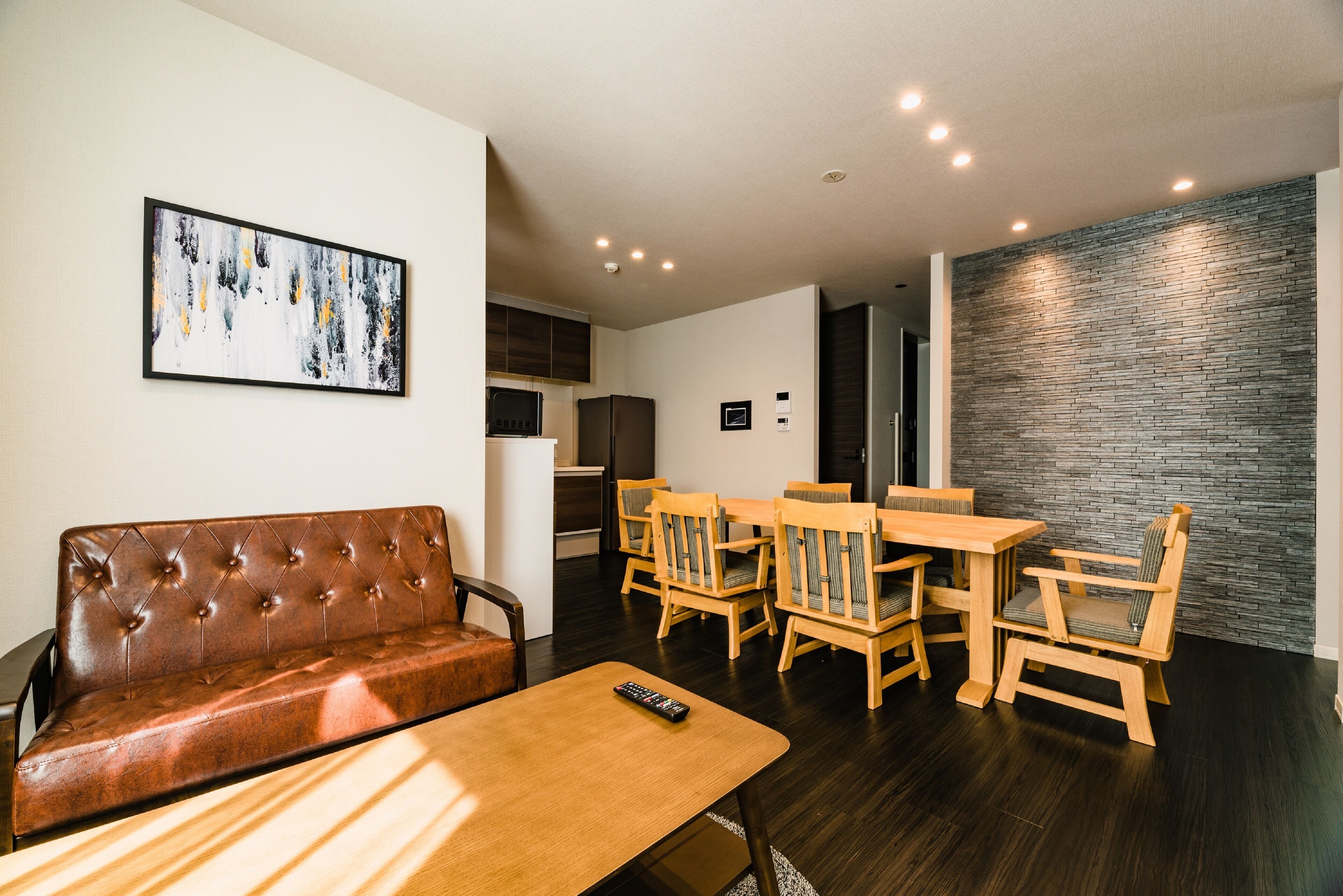 Uma sala de estar moderna com um sofá de couro marrom, mesa de jantar de madeira e cadeiras.