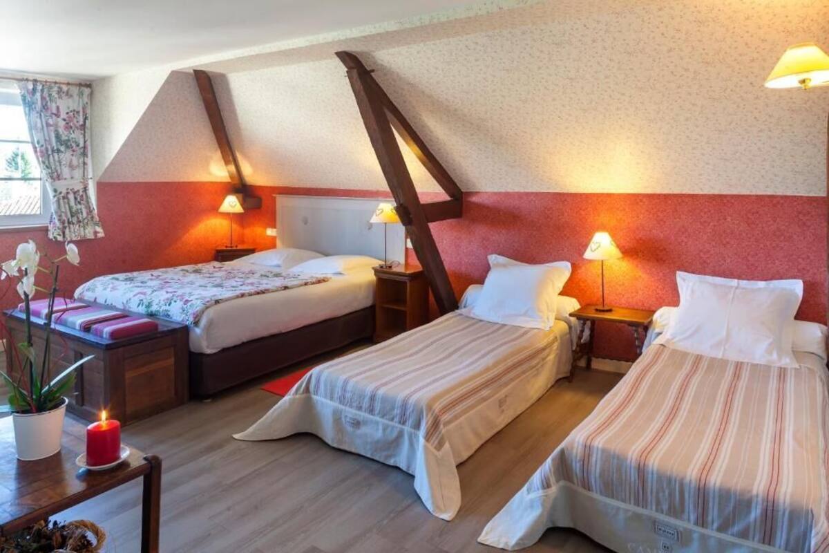 Quarto de hotel com duas camas de solteiro, teto de madeira e uma pequena mesa com uma vela.