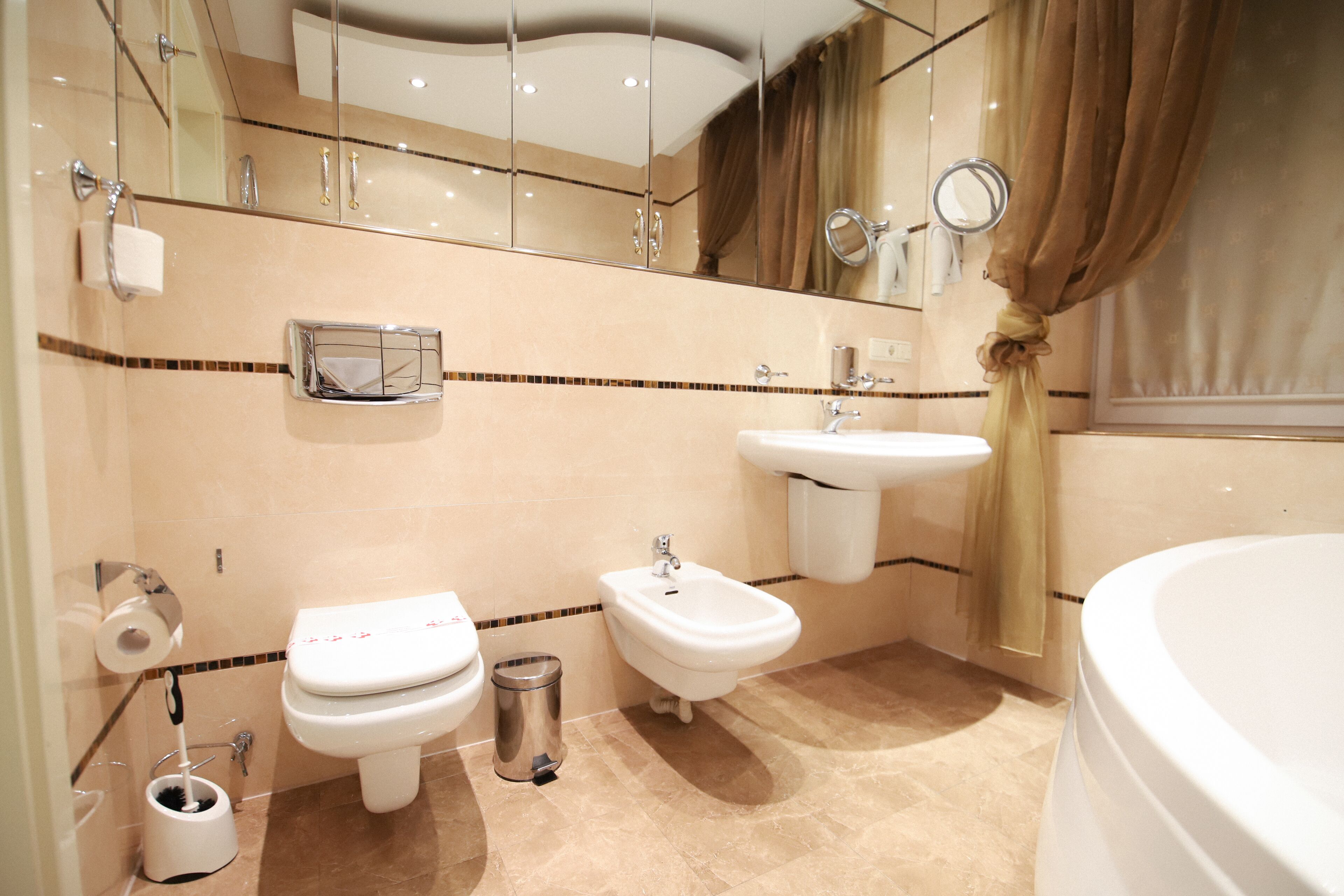 Uma casa de banho moderna com sanita, bidé, lavatório e banheira.