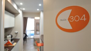 Interior moderno de hotel com cozinha, corredor e placa Delco 304 na parede.