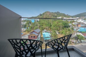 Uma varanda com duas cadeiras, vista para uma área residencial e uma montanha ao fundo.