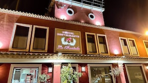 Um edifício com uma placa indicando "Hostal Restaurante La Barlola" e várias bandeiras, incluindo a bandeira da União Europeia.