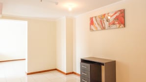 Quarto com um armário de madeira escura, uma luminária no teto e um quadro abstrato pendurado na parede.