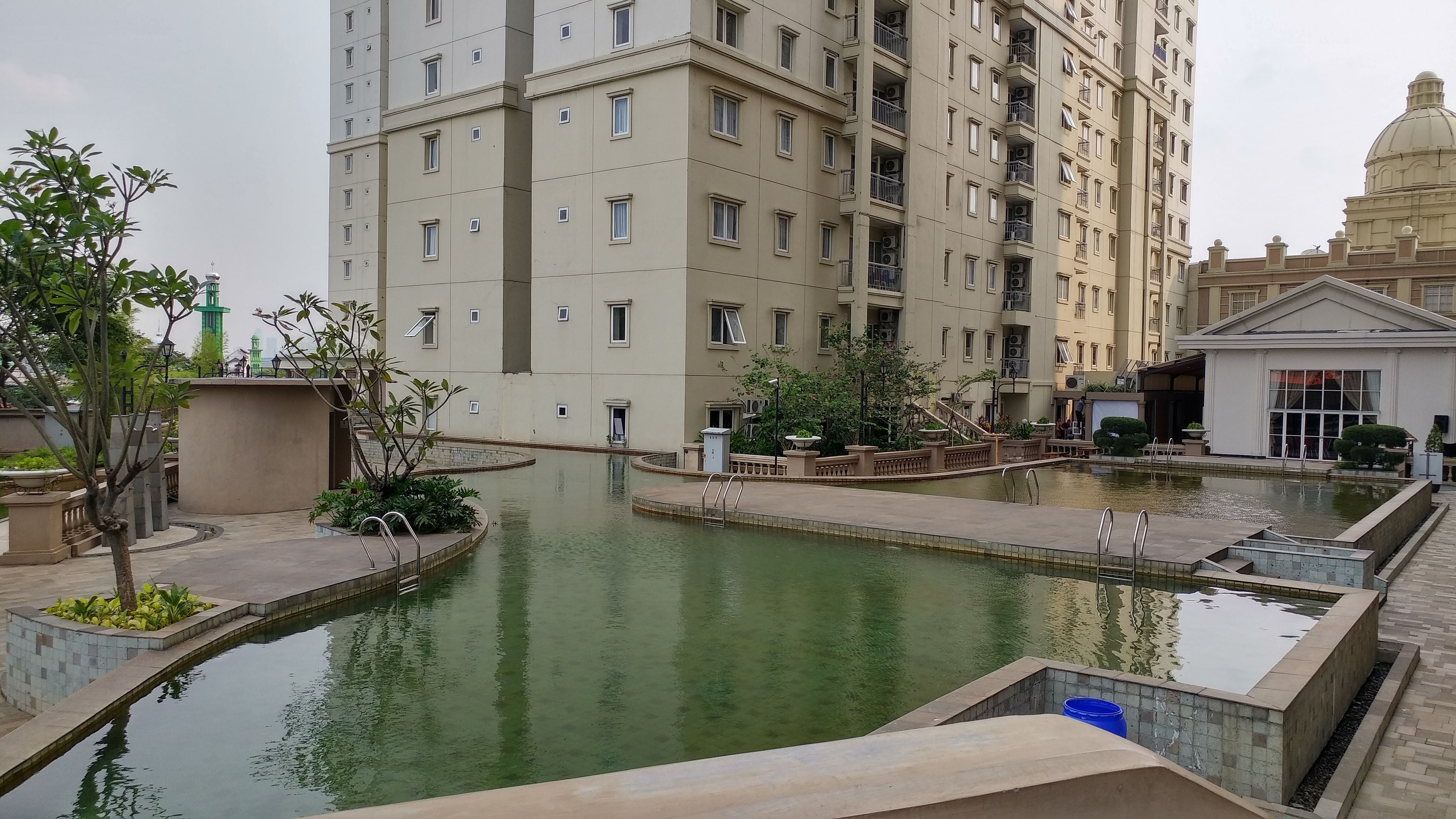 Um edifício residencial alto com várias varandas e área de piscina.