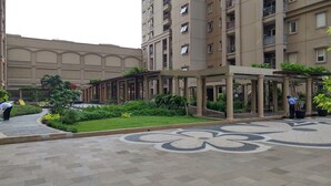 Um pátio com galeria coberta, área decorativa com azulejos e um edifício com várias varandas.