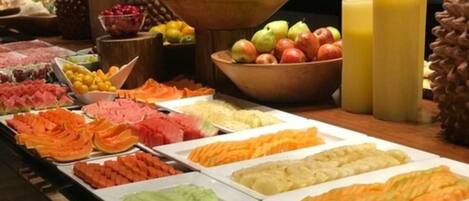 Buffet com diversos alimentos, incluindo frutas, legumes e carnes.