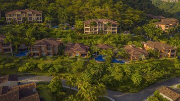 Um resort com vários edifícios, piscinas e vegetação exuberante.