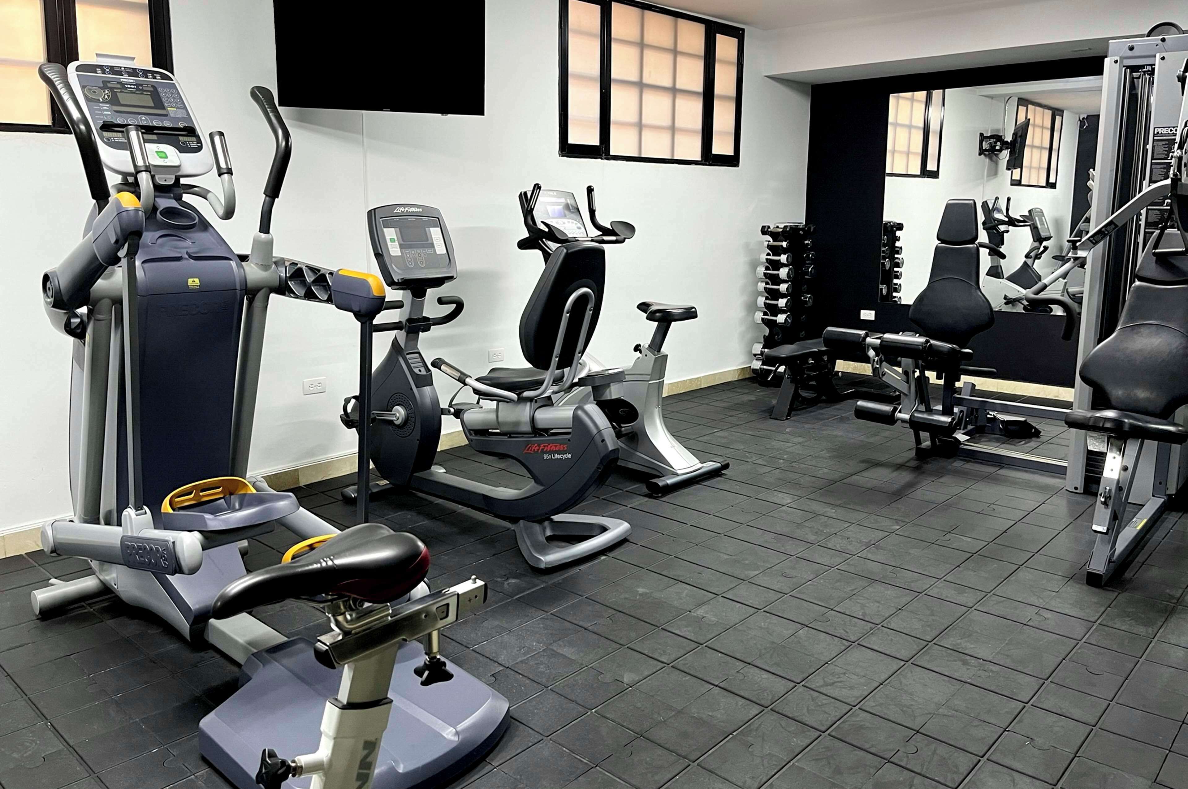 Academia com diversos equipamentos de exercícios, incluindo esteiras, bicicletas ergométricas e aparelhos de musculação.
