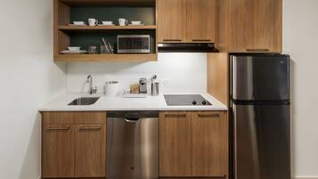 Uma cozinha moderna com armários de madeira, uma lava-louças de aço inoxidável, geladeira, micro-ondas e cafeteira.