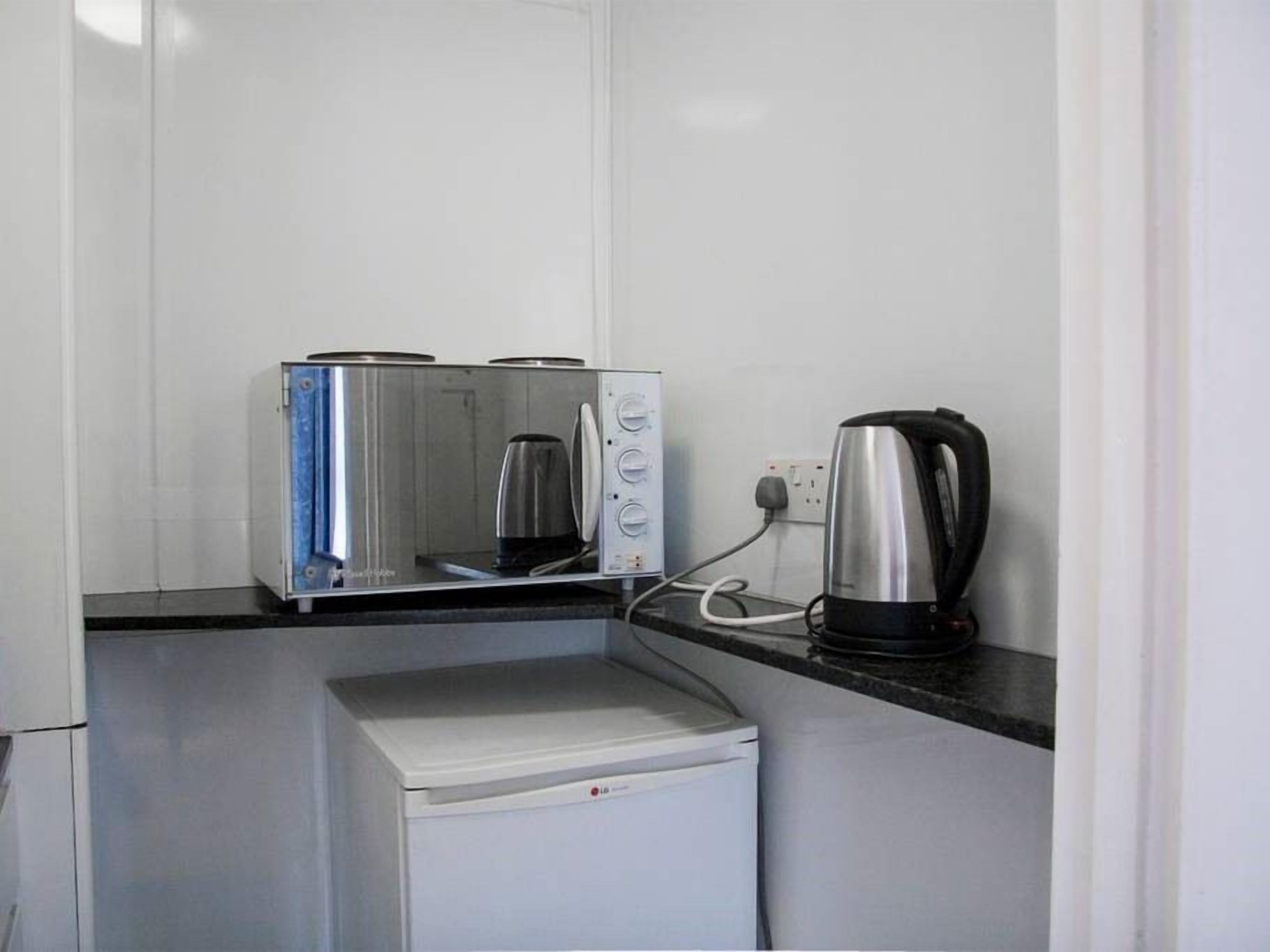 Uma cozinha compacta equipada com micro-ondas, torradeira e cafeteira.
