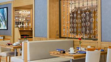 Uma sala de jantar moderna com móveis de madeira, um expositor de copos de vinho e disposição para sentar.