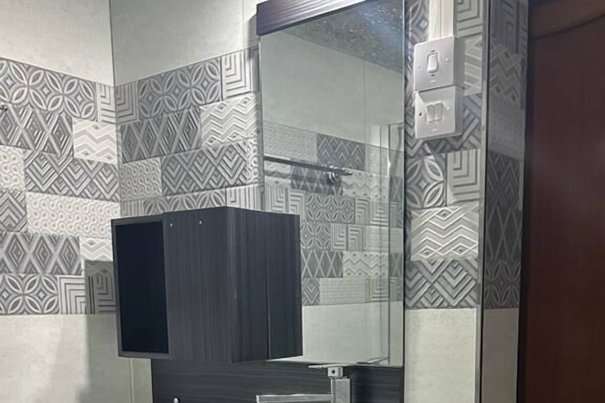 Um banheiro moderno com uma pia grande e branca, armários escuros e azulejos estampados.