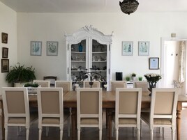 Uma sala de jantar com um espelho branco ornamentado, uma mesa de jantar de madeira e cadeiras bege.