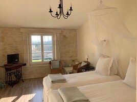 Quarto com cama, televisão, janela, cadeira e mesa.