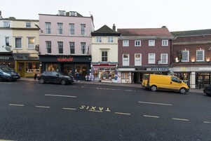 Uma rua com diversas lojas, incluindo Thai Terrace, Nandos, Viva Italia e um McDonald's.