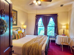 Quarto de hotel com cama, cadeira, mesa e janela com cortinas.
