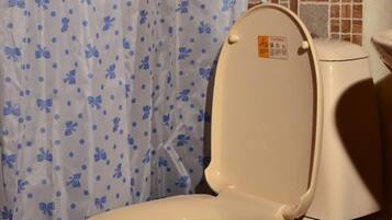 Sanitário com etiqueta de aviso, cortina de borboleta azul e parede revestida de azulejos.