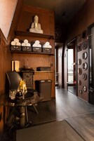 Interior moderno com uma estátua de Buda, prateleiras com toalhas, um relógio e uma porta com espelhos circulares.