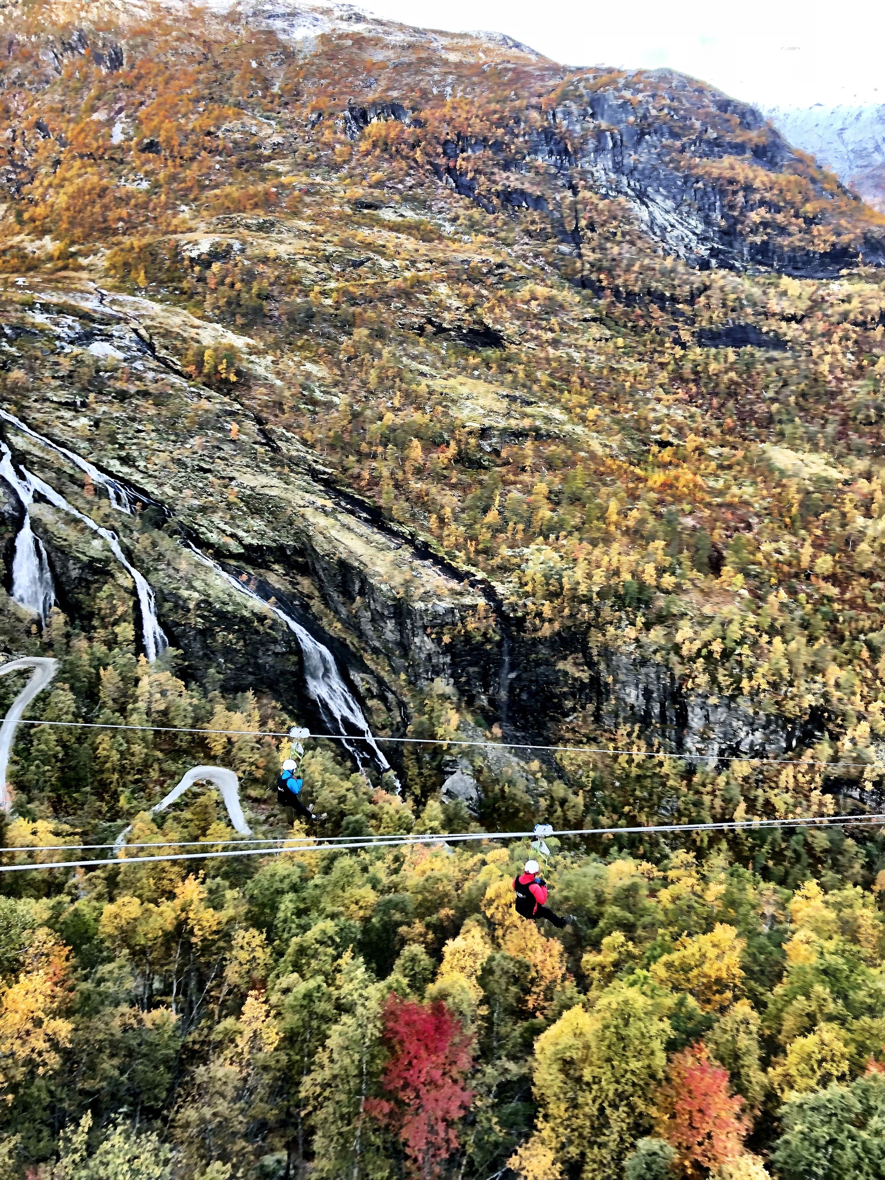 Paisagem montanhosa com estrada sinuosa e sistema de teleférico.