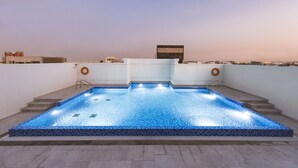 Uma piscina no terraço com degraus de acesso, rodeada por um horizonte urbano.