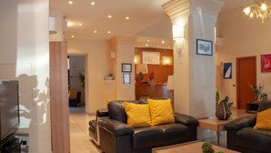 Uma sala de estar espaçosa com sofás de couro, uma TV de tela plana e um espaço de refeições com mesa e cadeiras.