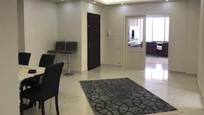 Quarto espaçoso com área de jantar, uma porta preta e vista para outro cômodo com um sofá.