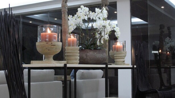 Um interior moderno com divisória de vidro, mesa com velas e cadeiras brancas.